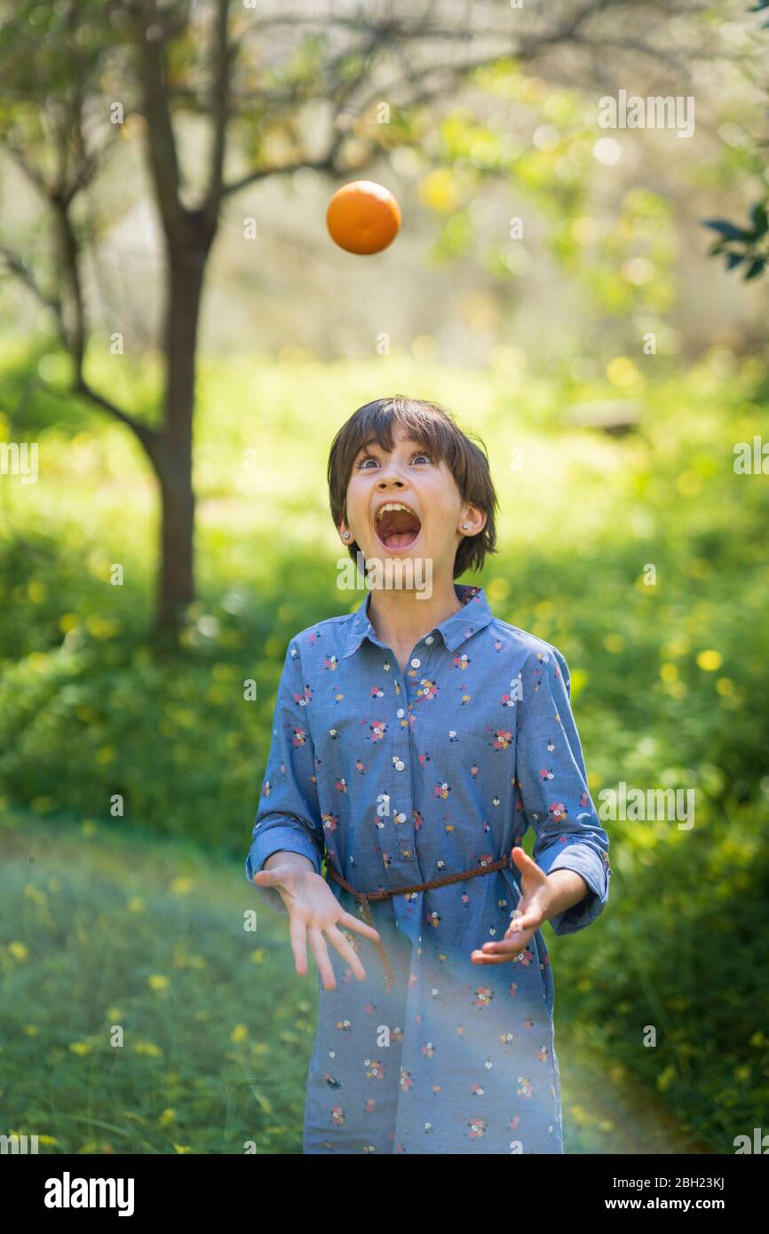 Happy girl throwing up orange in the countryside Stock Photo - Alamy