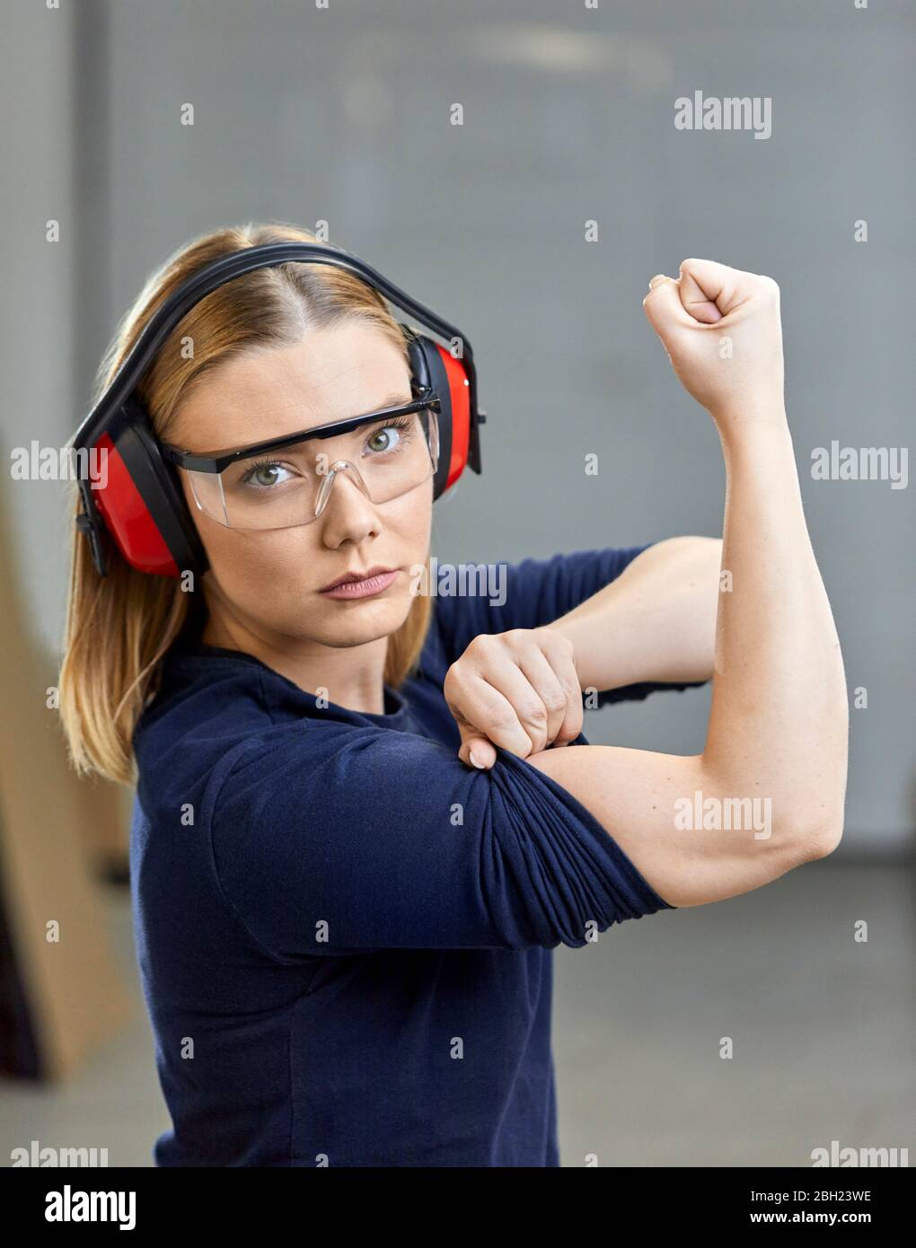 Portrait of female worker flexing her muscles Stock Photo - Alamy