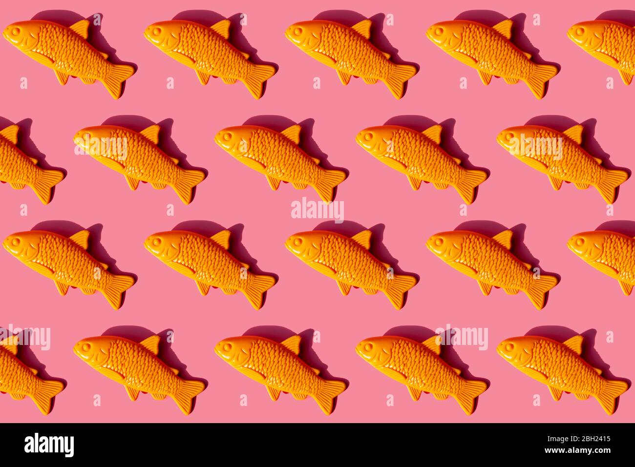Pattern of yellow plastic fish against pink background Stock Photo - Alamy