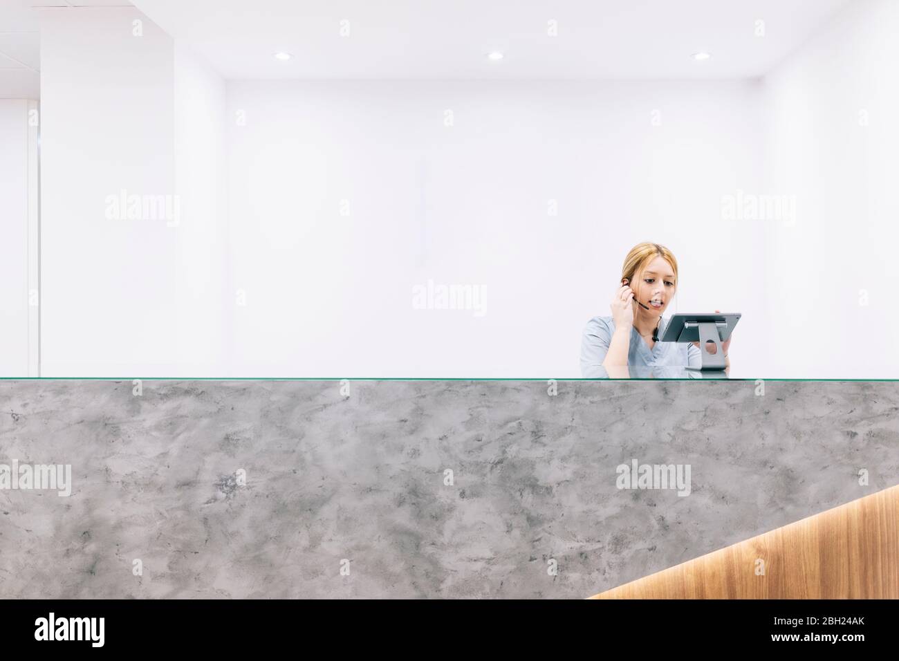 Receptionist at reception desk of a medical practice using headset and ...
