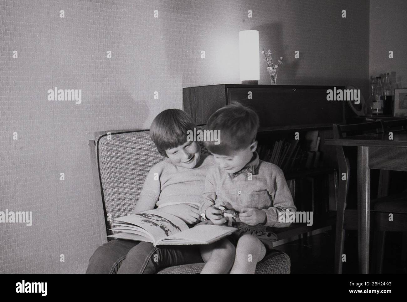 1962, historical, inside a room, sitting on a chair with her little ...