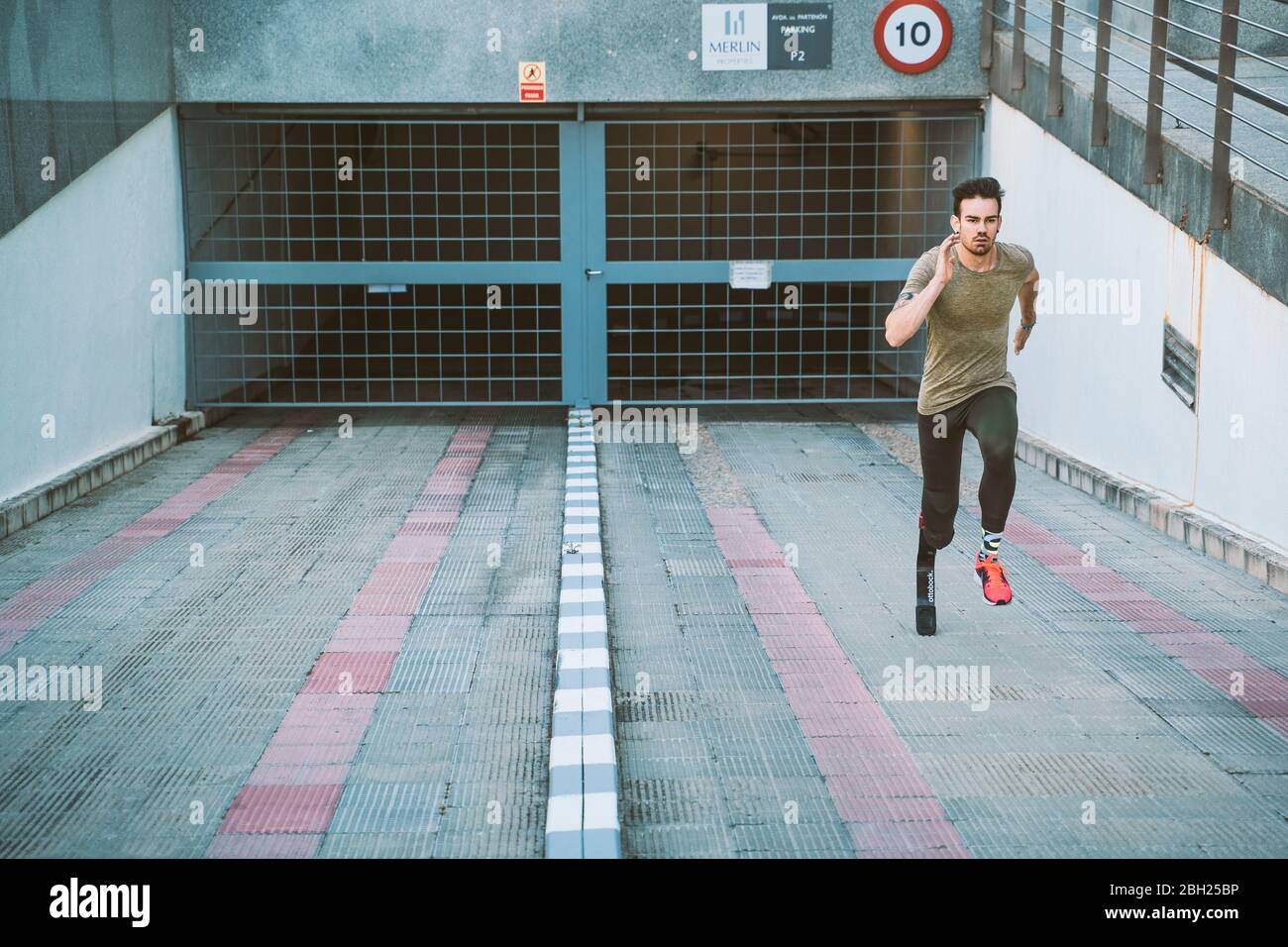 Disabled athlete with leg prosthesis running up ramp at a garage Stock ...