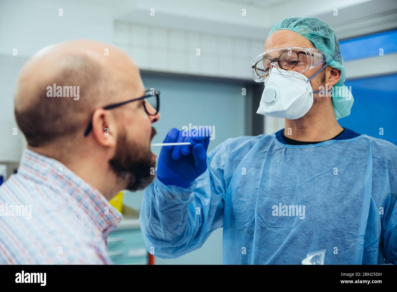 Doctor in hospital taking a swab from patient's mouth Stock Photo - Alamy
