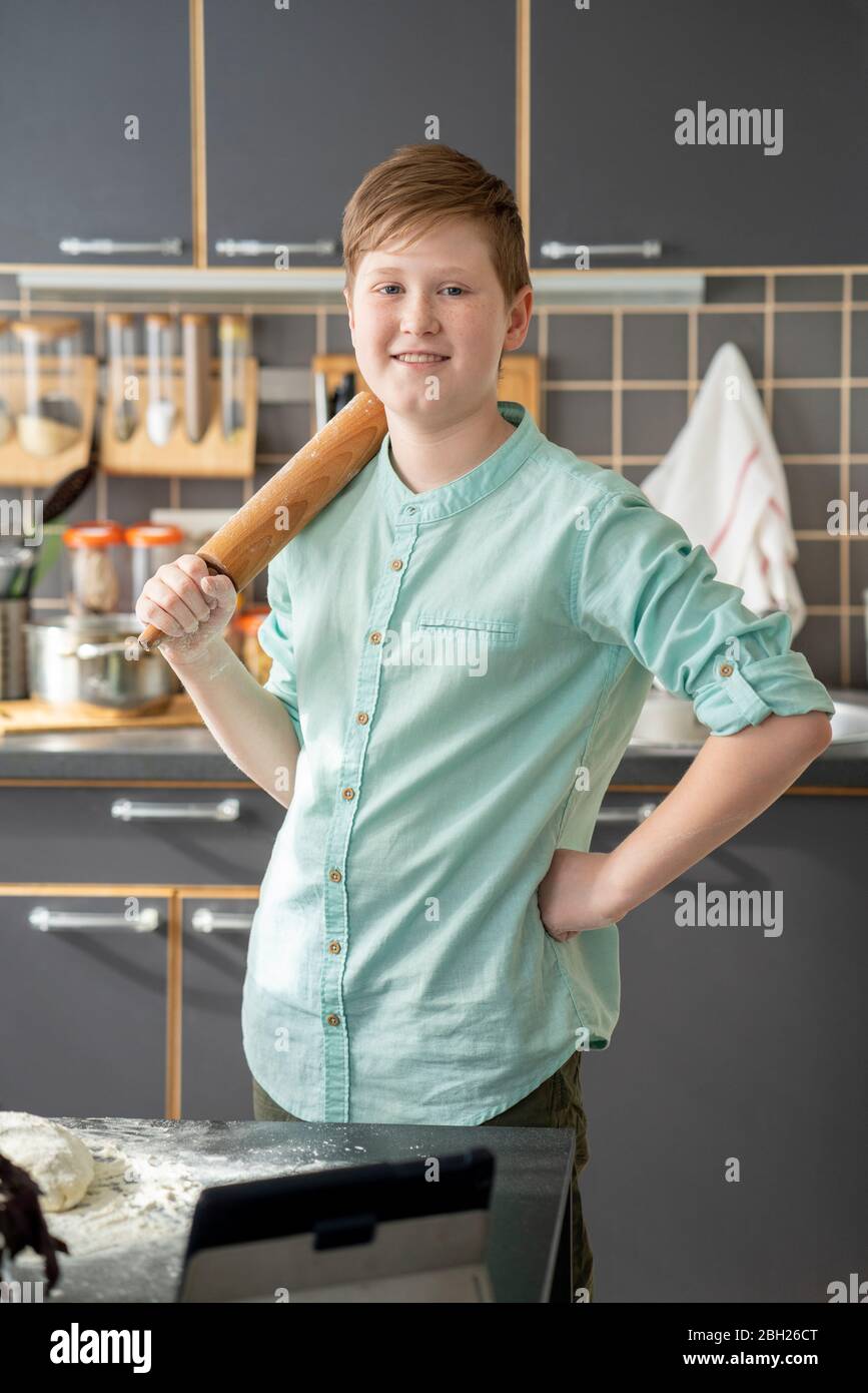 Portrait of smiling boy with rolling pin in the kitchen Stock Photo - Alamy