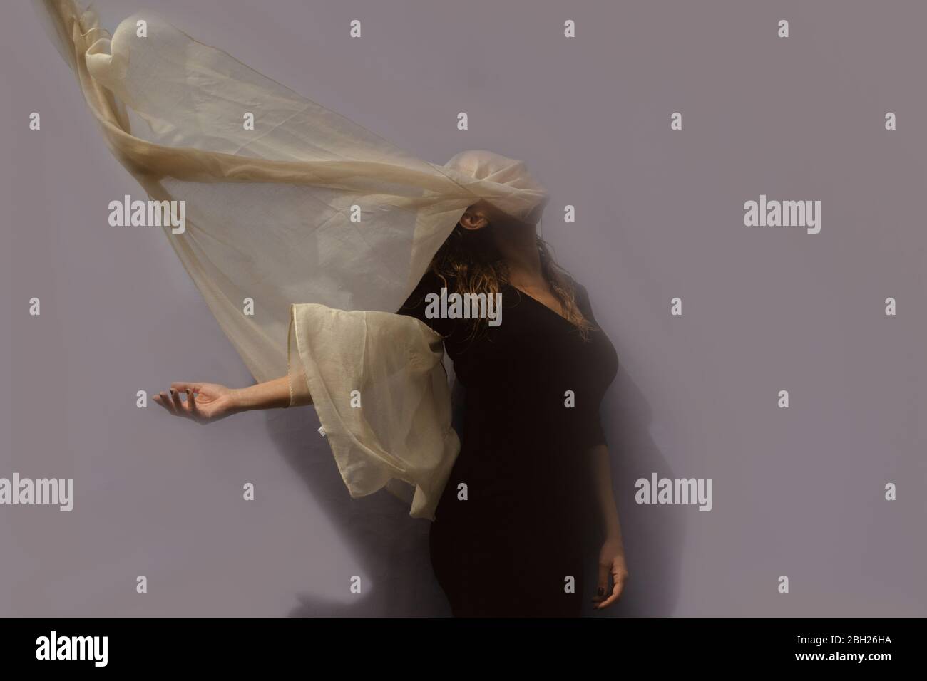 Woman under cloth in front of gray wall Stock Photo - Alamy