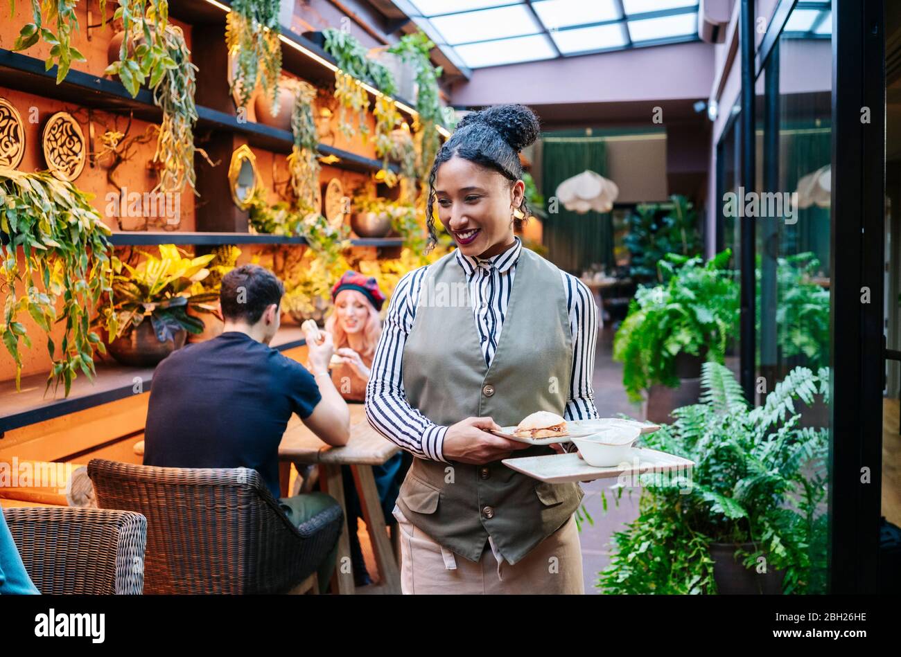 People sitting in restaurant, while waitress is serving food Stock ...