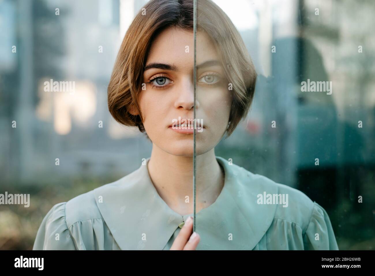 Portrait of woman with half of her face behind a glass Stock Photo - Alamy