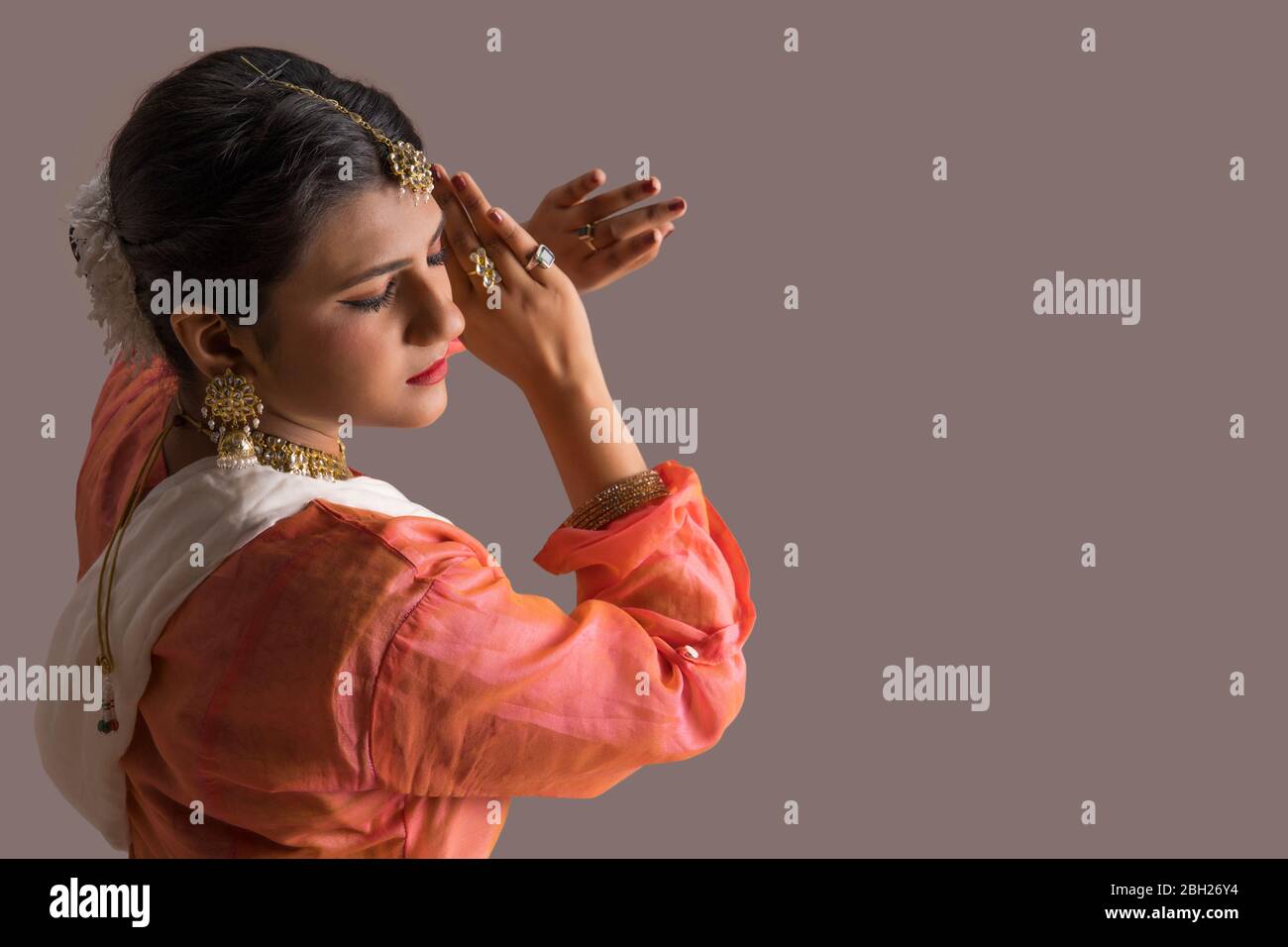 Beautiful kathak dancer performing through her expressions over a plain ...