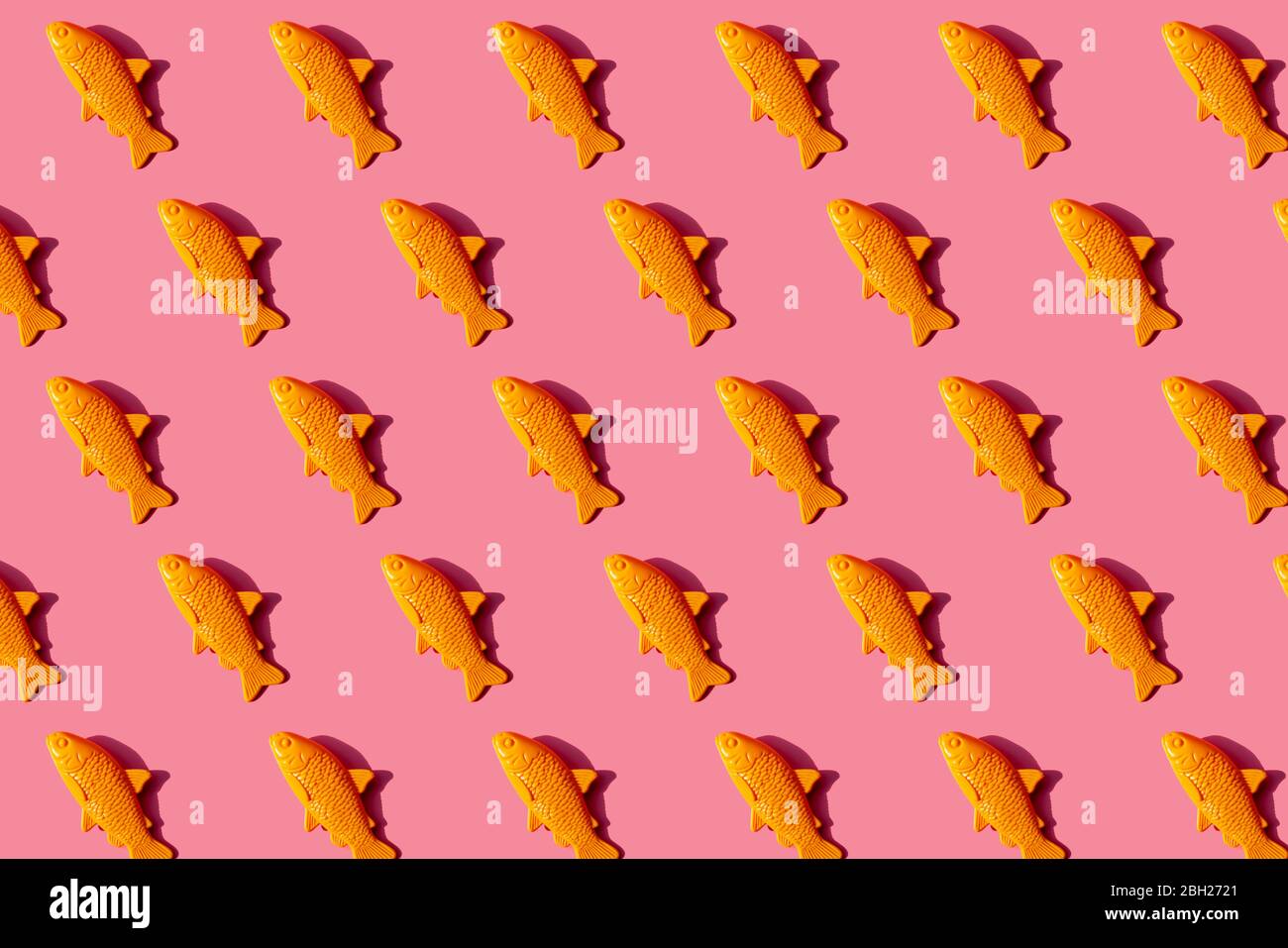 Pattern of yellow plastic fish against pink background Stock Photo - Alamy