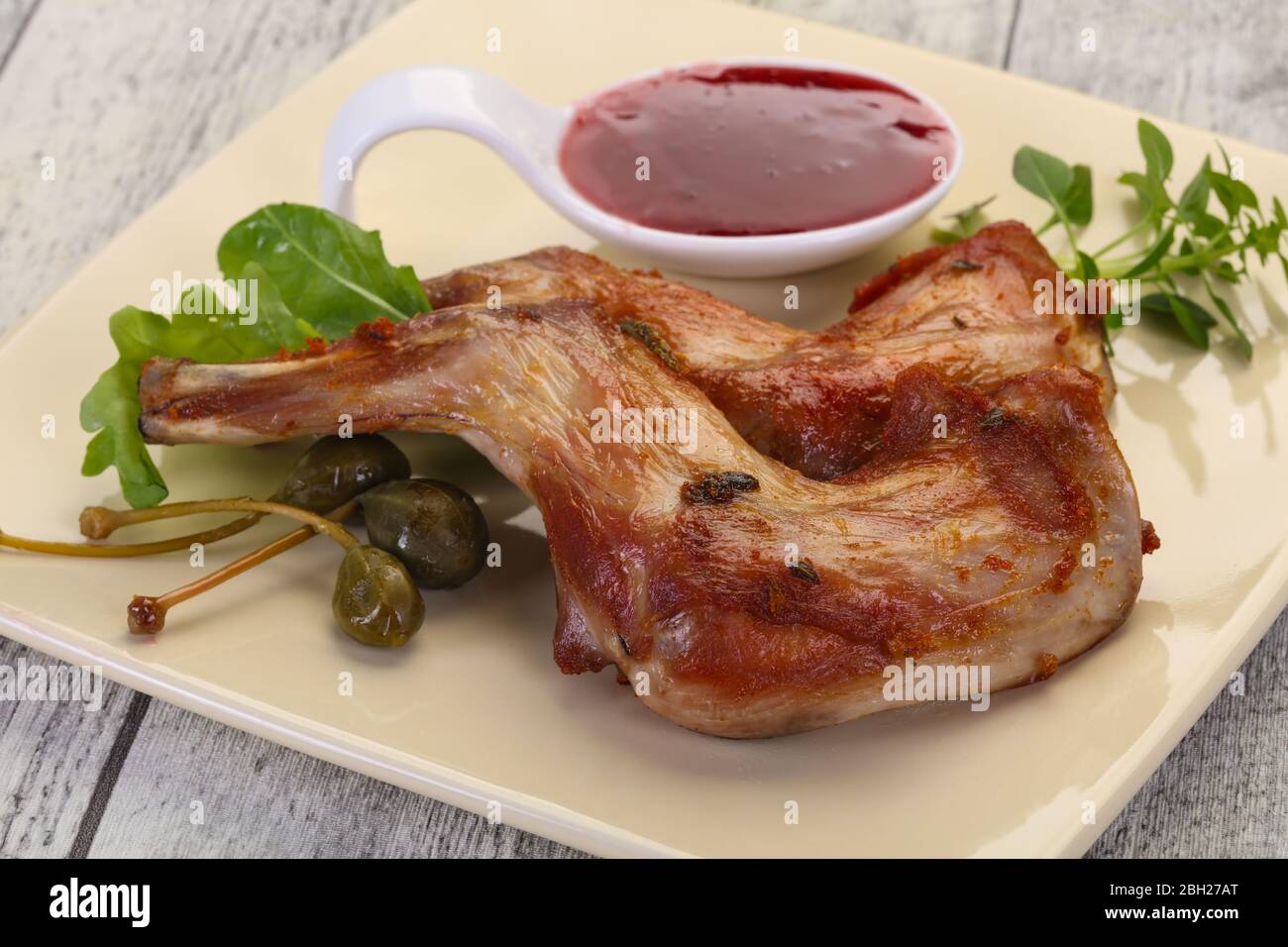 Roasted rabbit legs with cowberry sauce Stock Photo - Alamy