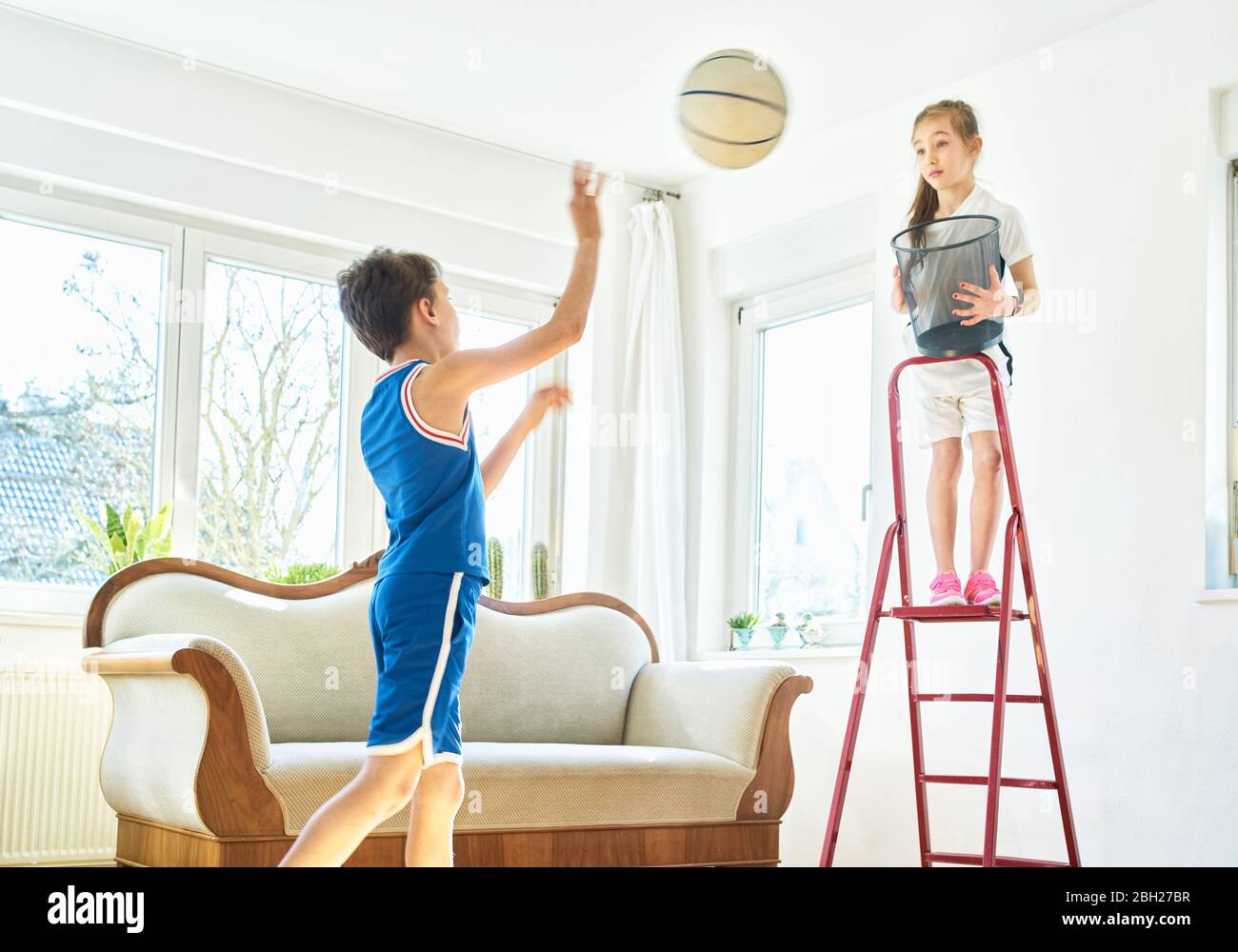 Boy and girl playing basketball in living room Stock Photo - Alamy