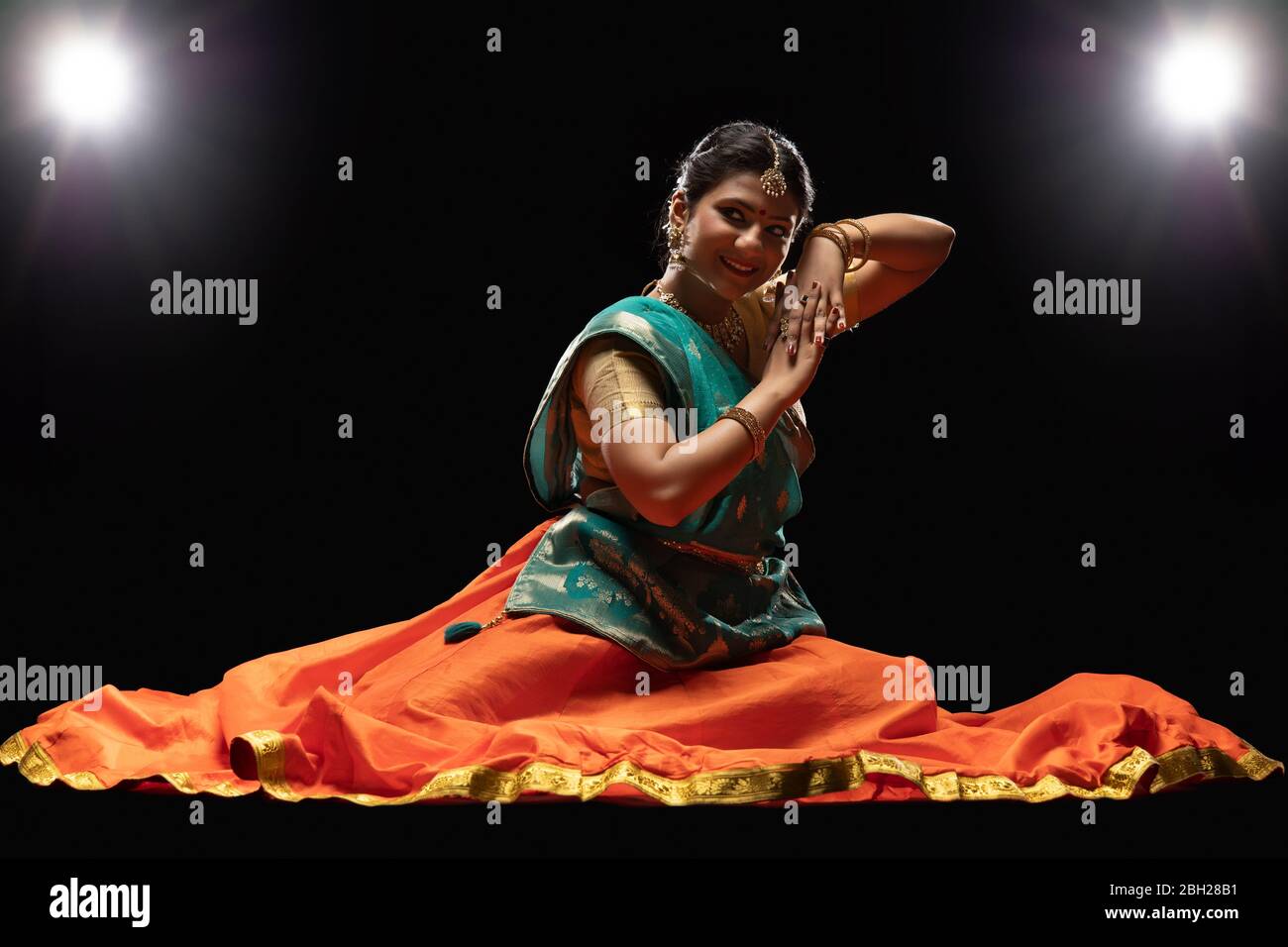 Kathak dancer sitting gracefully in front of a dark background Stock ...
