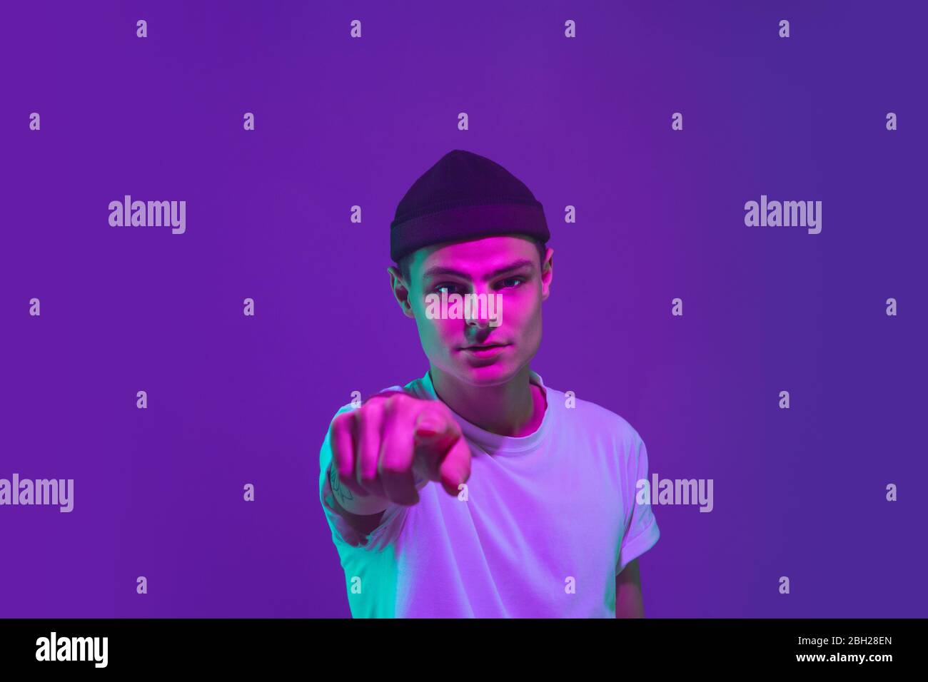 Pointing, choosing. Caucasian man's portrait isolated on purple studio ...