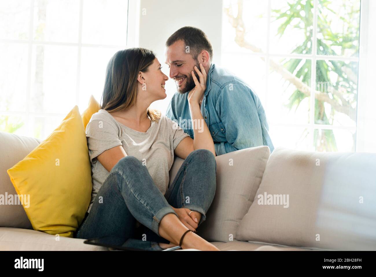 Affectionate couple in love about to kiss while relaxing at home on ...