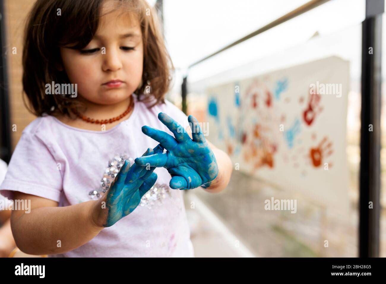 Little girl messing around with her painted hands Stock Photo - Alamy