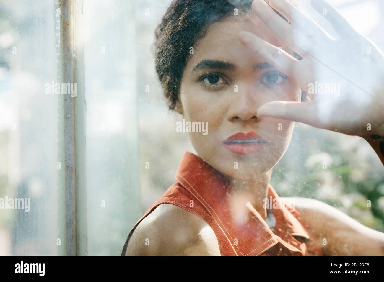 Portrait of young woman behind glass pane Stock Photo - Alamy