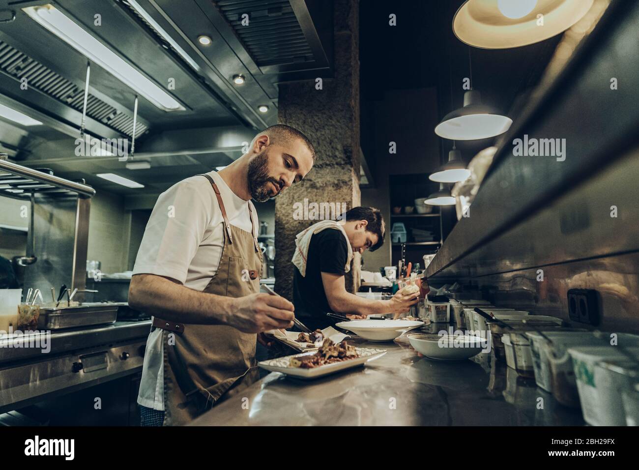 chefs in restaurant arranging food on plates for serving Stock Photo ...