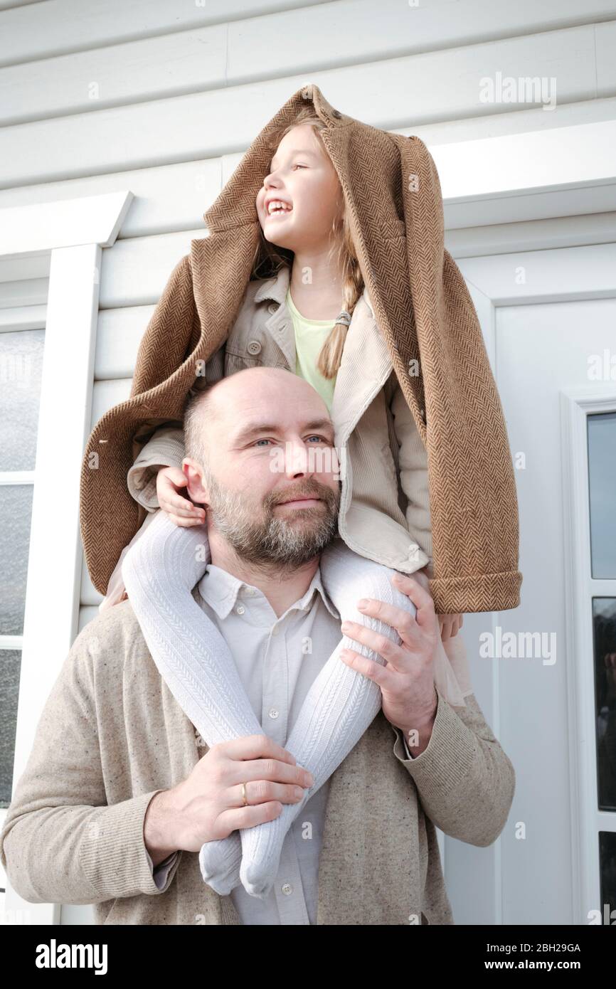 Portrait of father with happy daughter on his shoulders in front of ...
