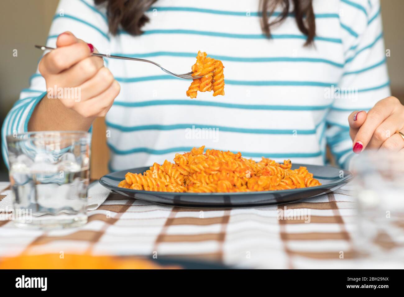 Woman eating pasta at dining table at home Stock Photo - Alamy