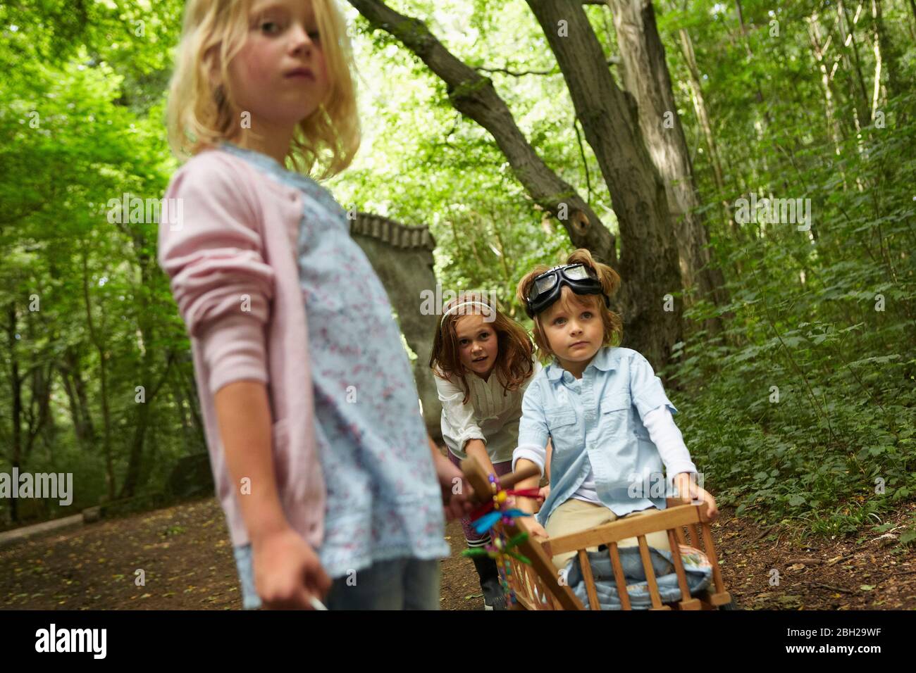 Children with hand cart playing in forest Stock Photo - Alamy