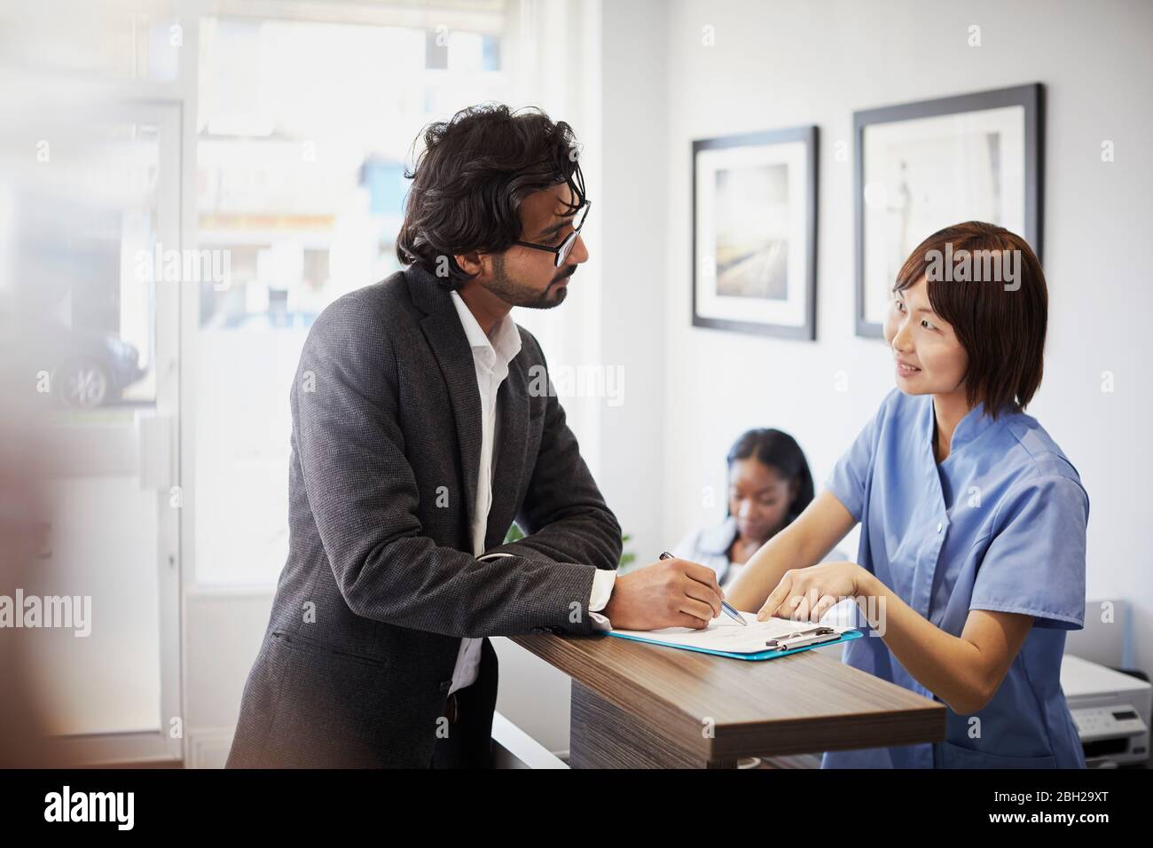 Patient at reception desk of a dental practice Stock Photo - Alamy