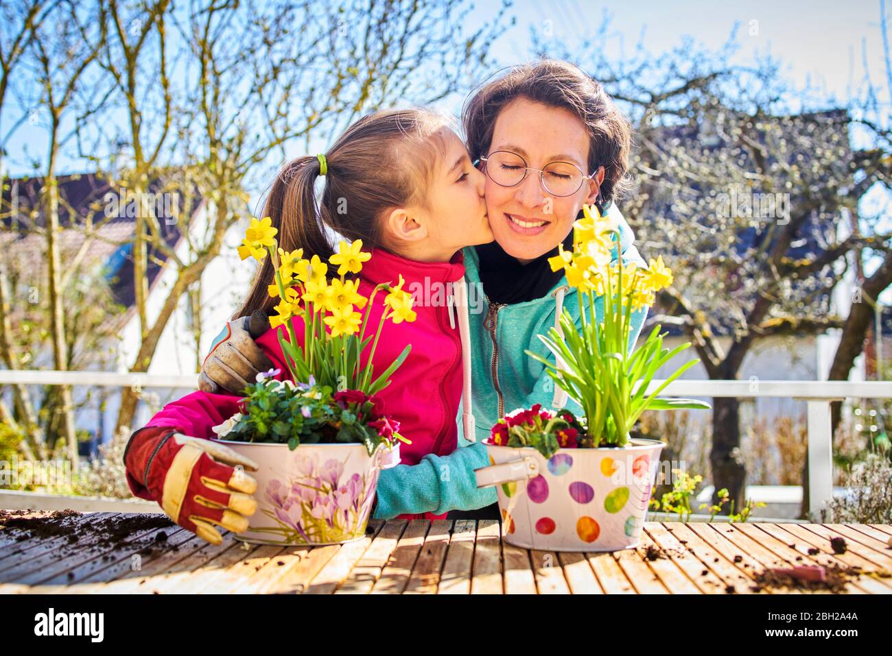 Mother and daughter planting flowers together on balcony Stock Photo ...