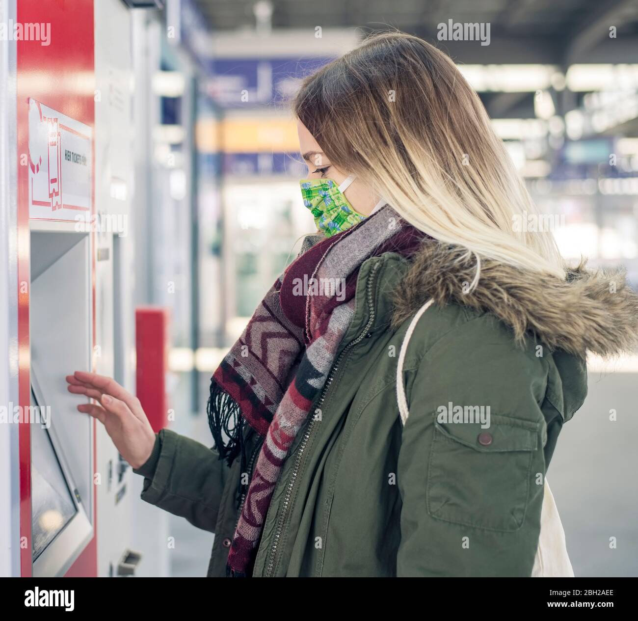 Young woman wearing mask using ticket machine at the station Stock ...