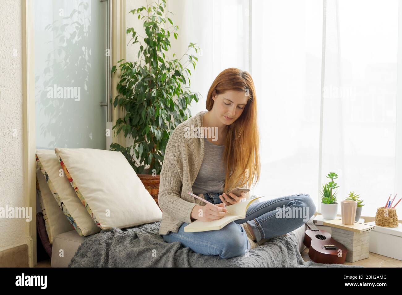 Young woman taking notes at home Stock Photo - Alamy