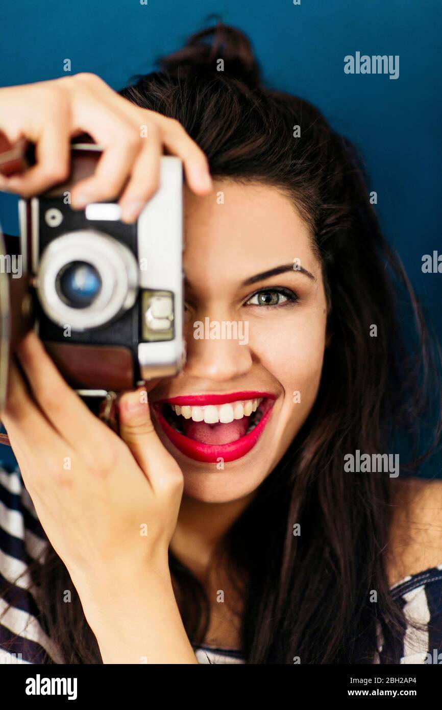 Portrait of young woman with red lips taking picture of viewer with ...