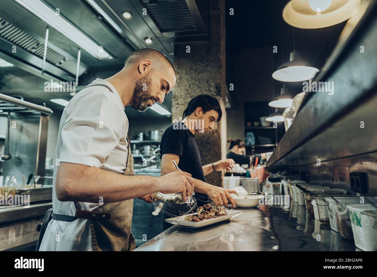 chefs in restaurant arranging food on plates for serving Stock Photo ...