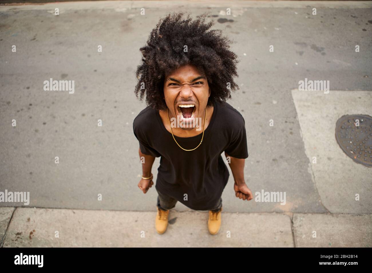 Portrait of screaming young man with afro standing on the street Stock ...