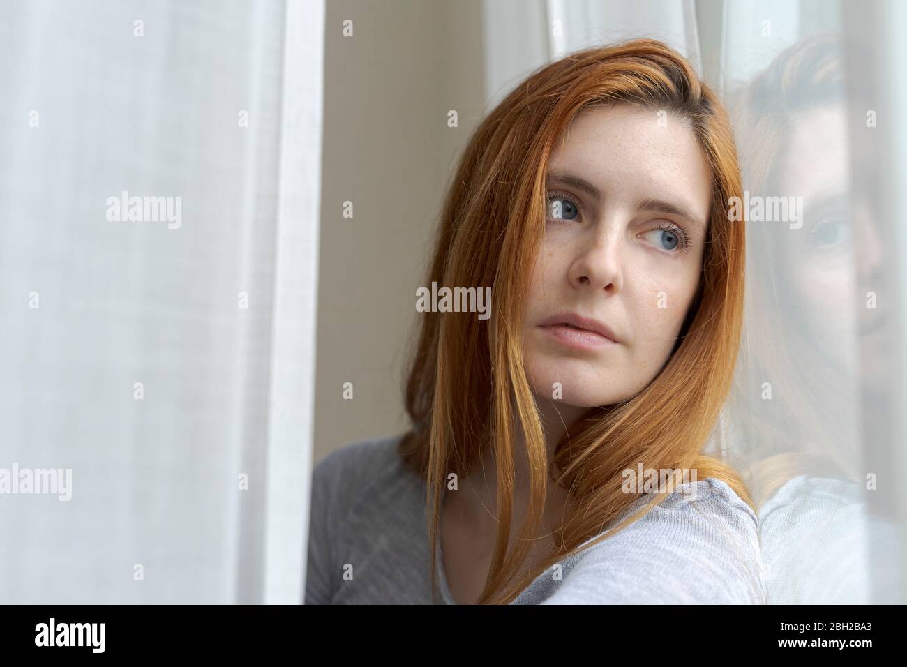 Portrait of serious young woman looking out of window Stock Photo - Alamy