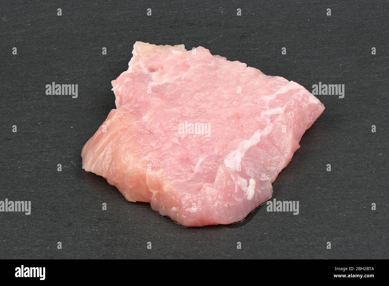 Fresh raw pork slice isolated on black slang stone. High resolution ...