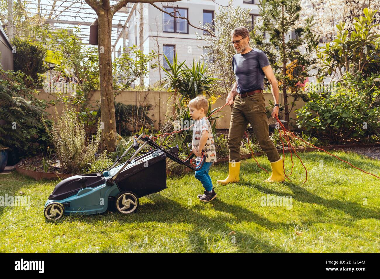 Father and son mowing the lawn together Stock Photo - Alamy