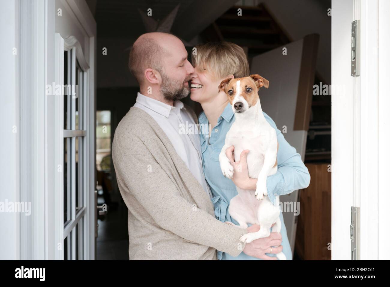 Happy couple with dog kissing at the entrance of their house Stock ...