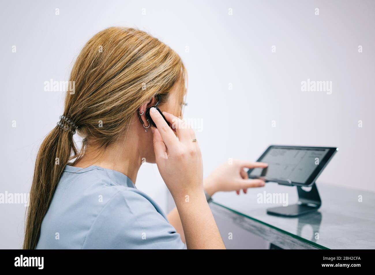 Receptionist at reception desk of a medical practice using headset and ...