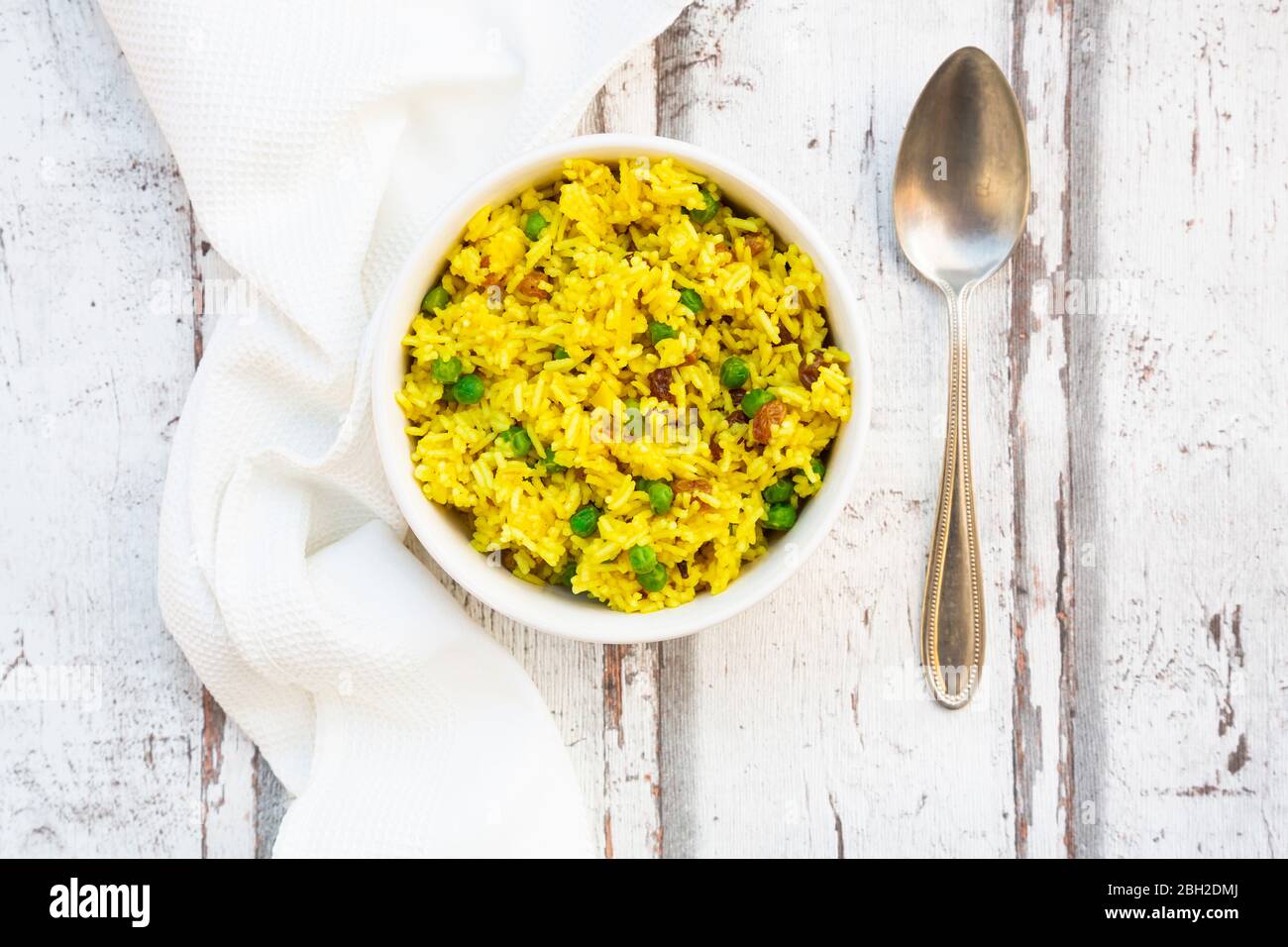 Bowl of pilau rice with green peas, raisins and turmeric Stock Photo ...