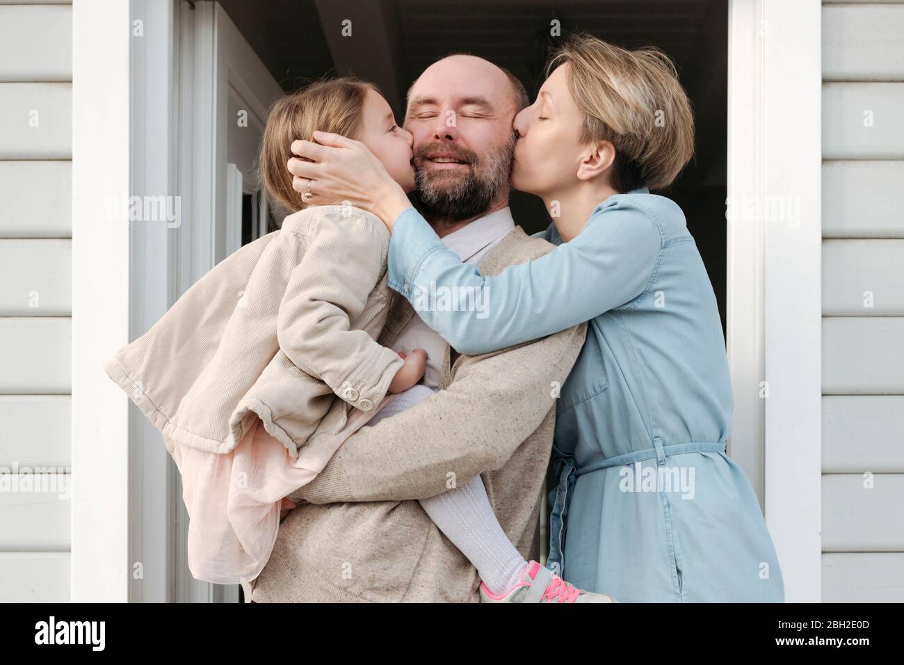 Happy family hugging and kissing in front of their house Stock Photo ...