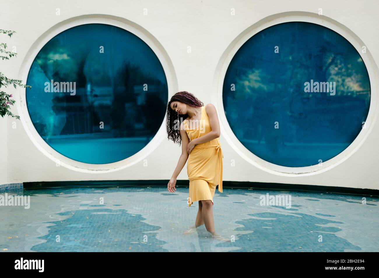 Young woman wearing yellow summer dress dancing in pool Stock Photo - Alamy