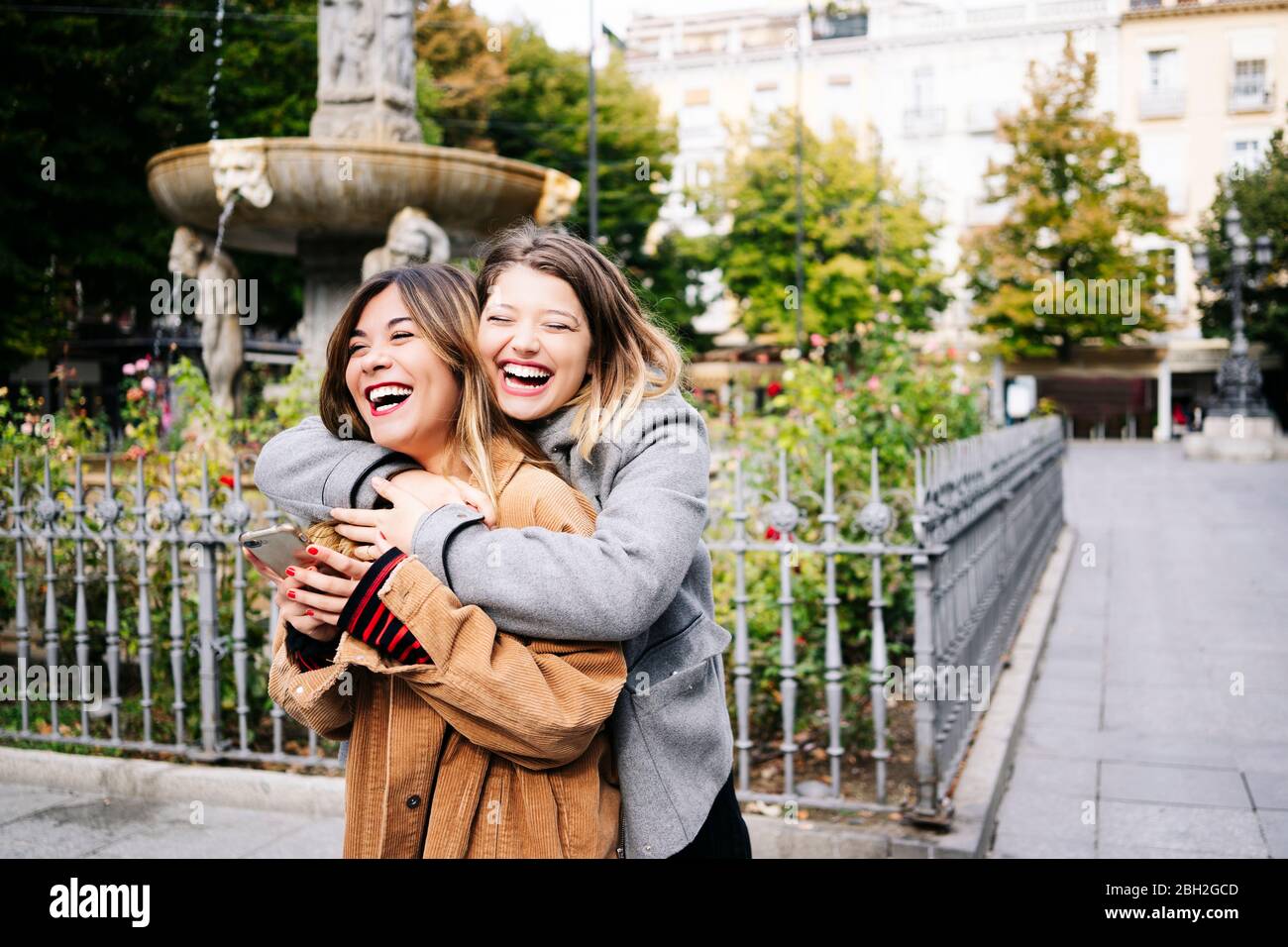Two happy young women hugging in the city Stock Photo - Alamy
