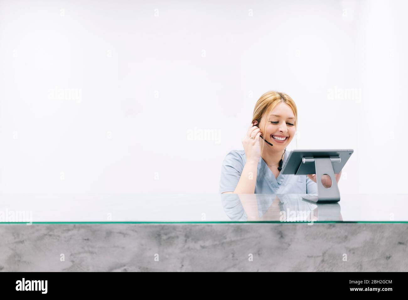 Smiling receptionist at reception desk of a medical practice using ...
