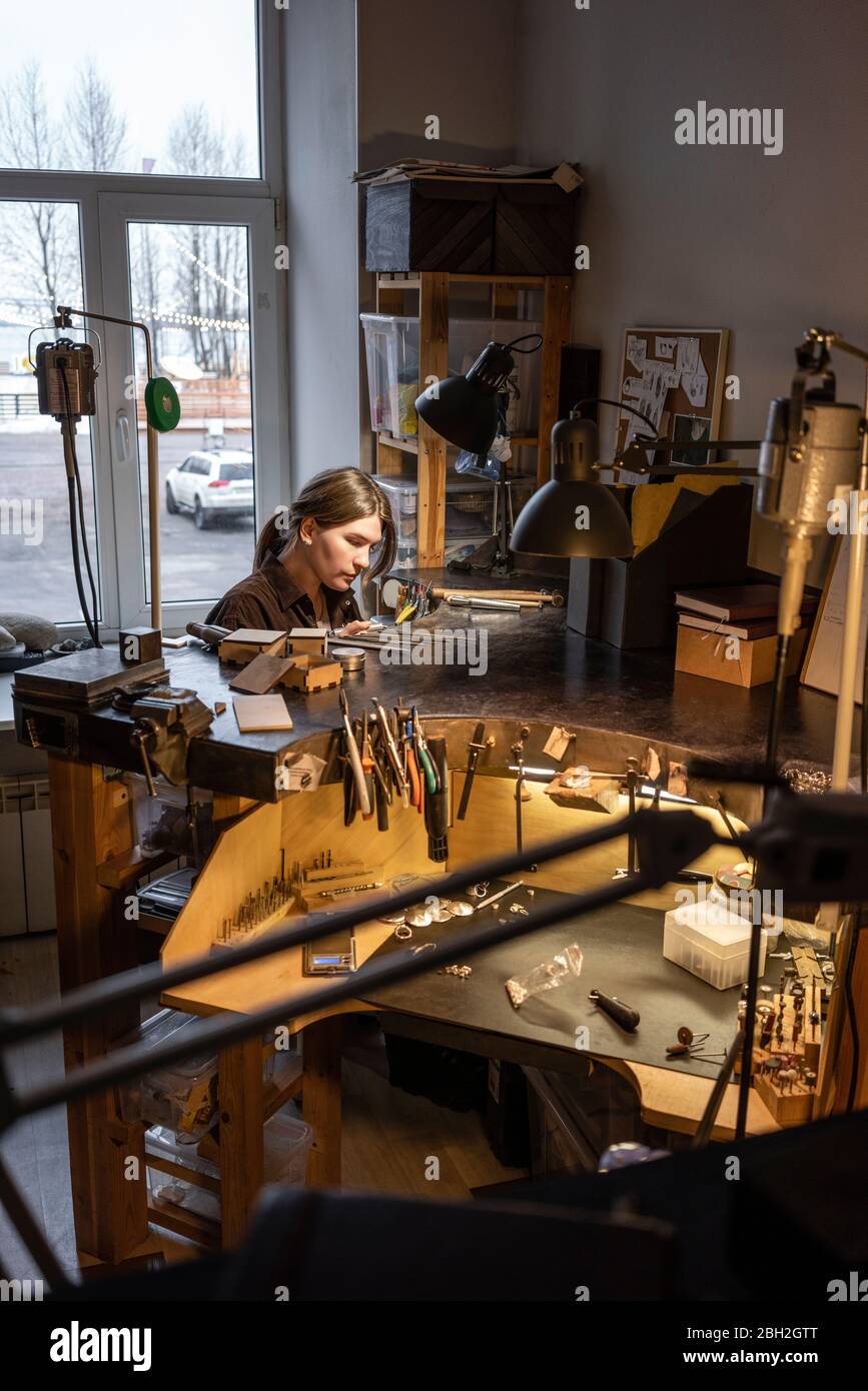 Female goldsmith working on her workbench in the workshop Stock Photo ...