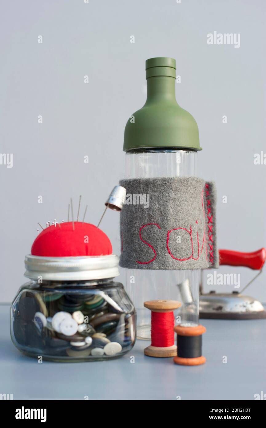 Mason jar with sewing buttons, pin cushion, spools of thread, thimble ...
