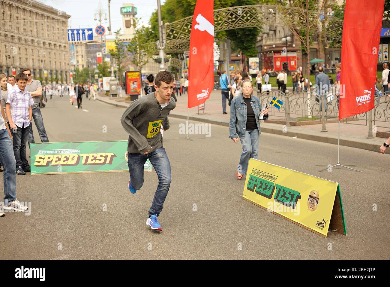 Young man running down the street during speed test attraction, people ...