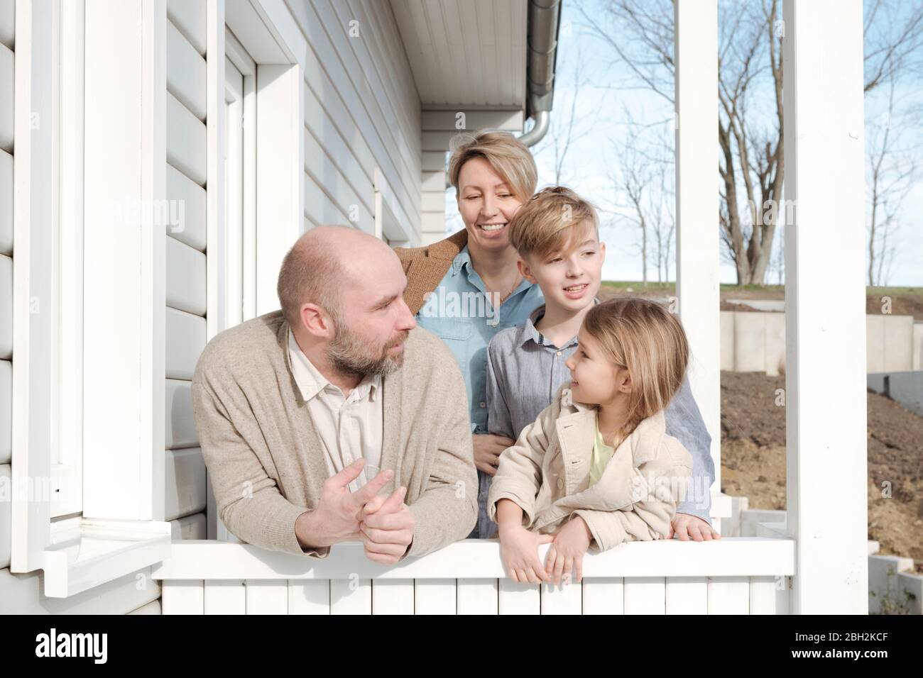 Happy family talking on porch of their house Stock Photo - Alamy