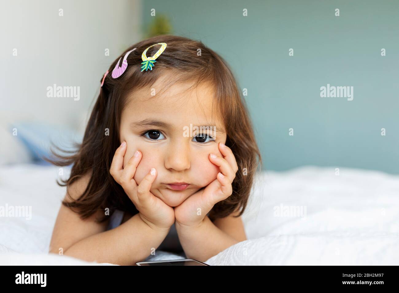 Portrait of bored little girl lying on bed Stock Photo - Alamy