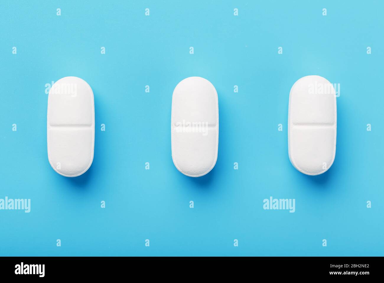 Three medicinal tablets in a row on a blue background, isolate Stock ...