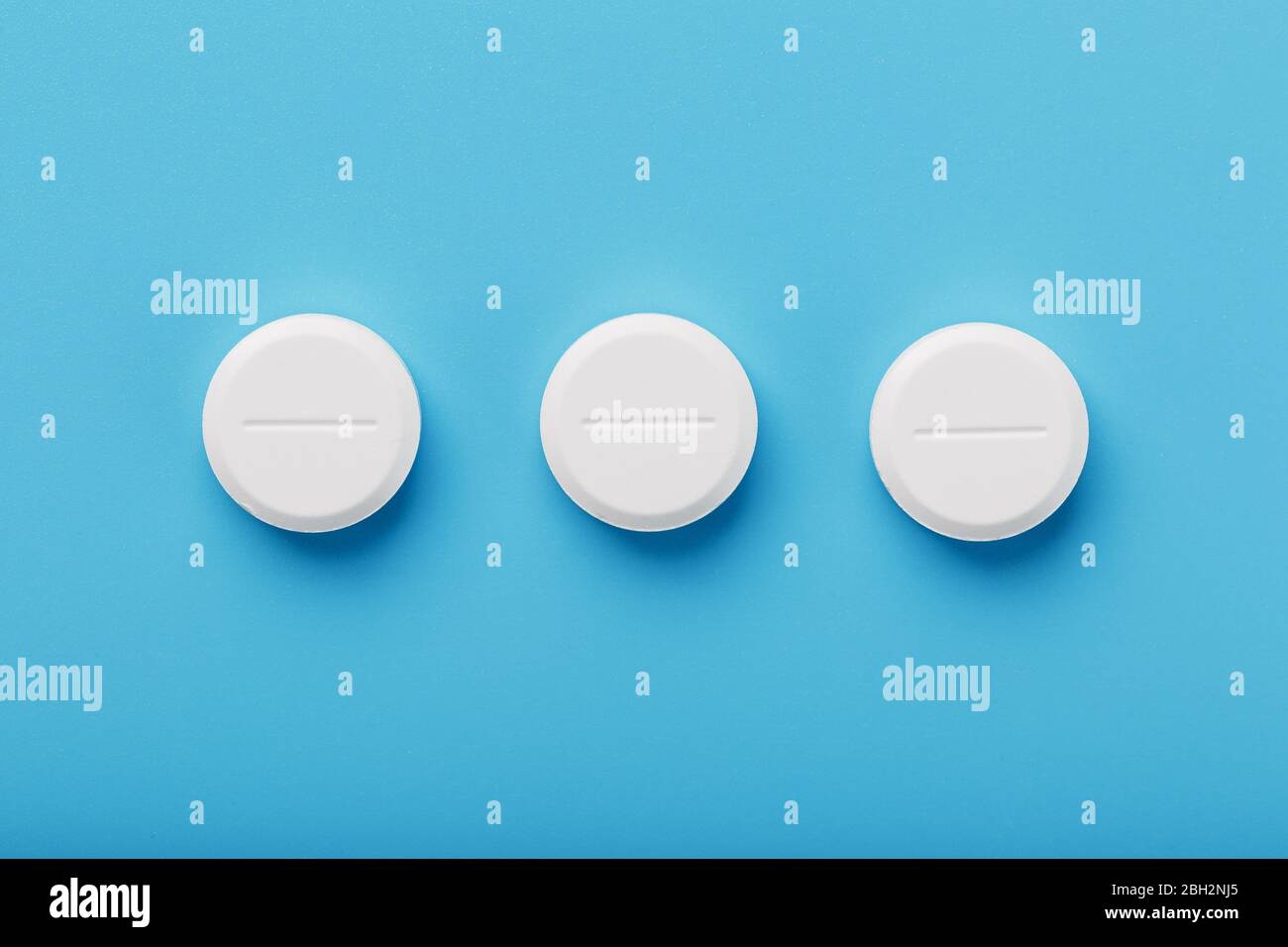 Round medicinal tablets lie in a row on a blue background, isolate ...