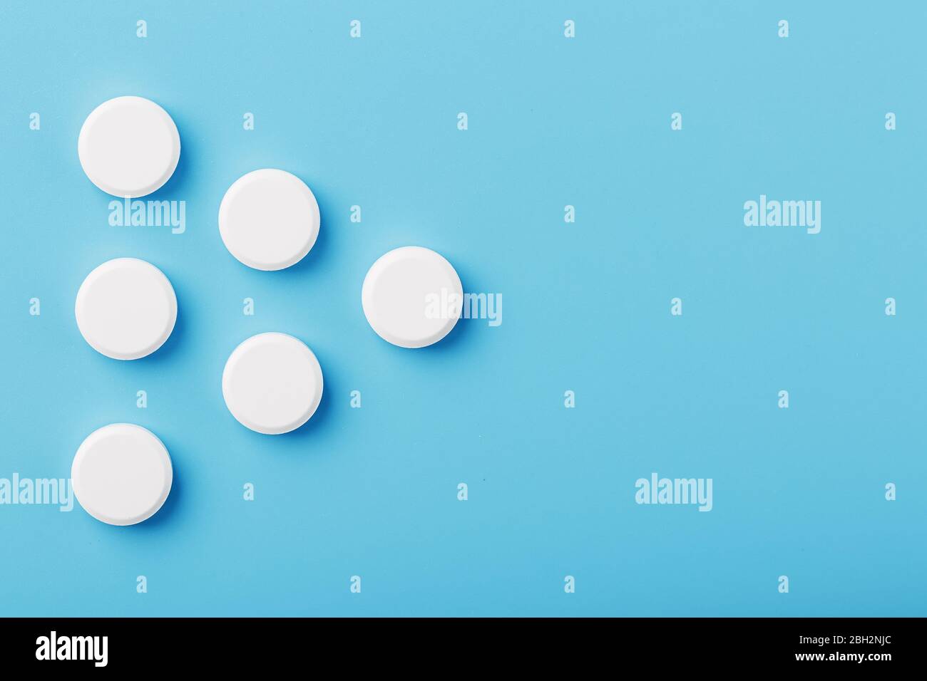 Round medicinal tablets in the shape of a triangle on a blue background ...