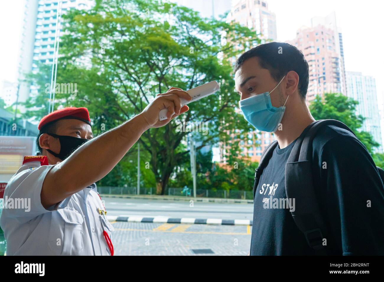 A security guard at the entrance to the mall measures the temperature ...